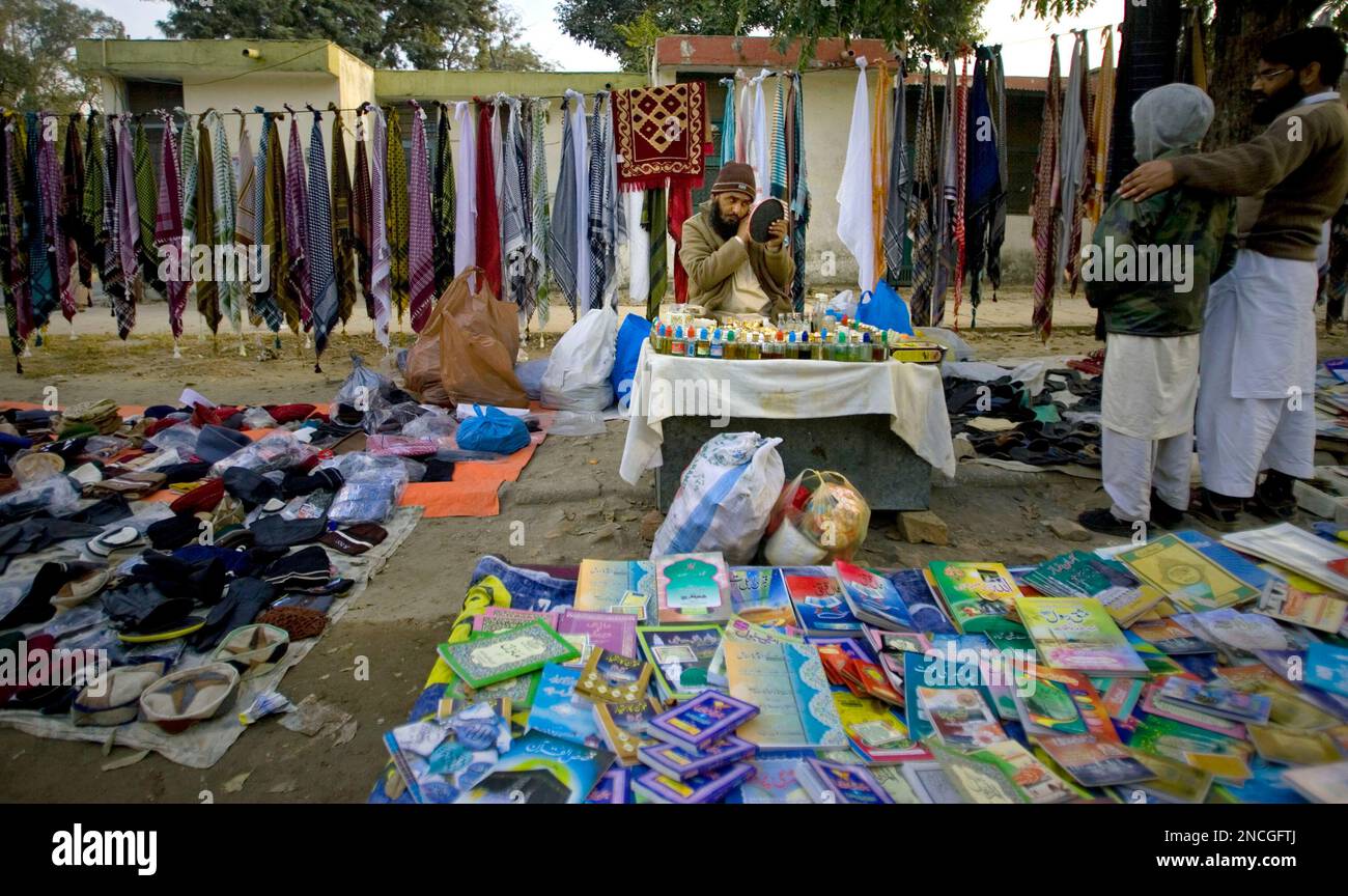 A Pakistani vendor trims his beard during free time on his stall at a ...