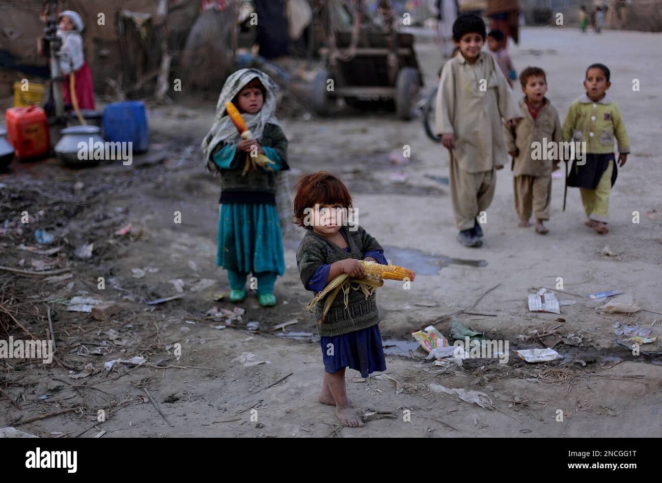 An Afghan refugee girl, center, looks on while gathering with other ...