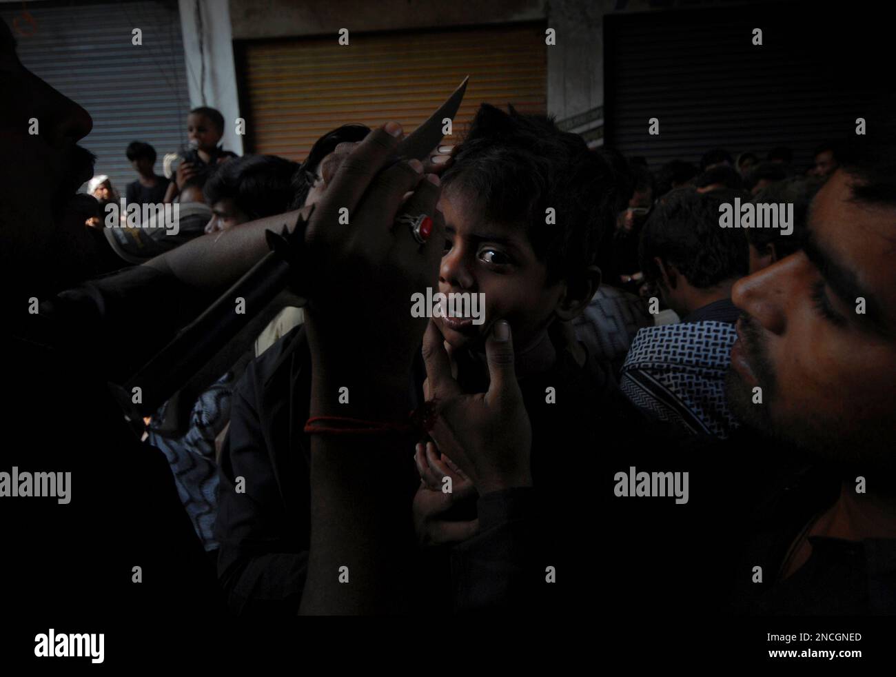 An Indian Shiite Muslim prepares to put a cut on the forehead of a ...