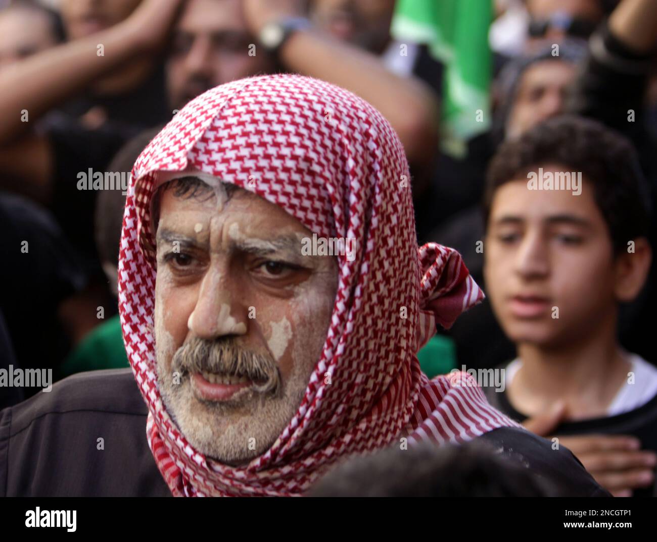 An unidentified Bahraini man, mud coating his face, participates in a ...