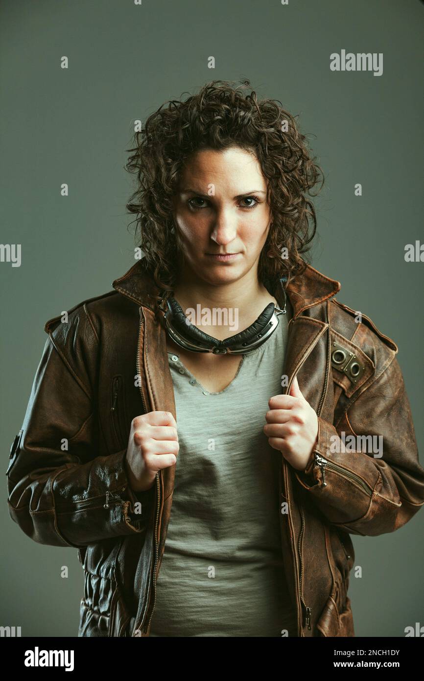 Frontal portrait of a female biker in leather jacket and goggles. She ...