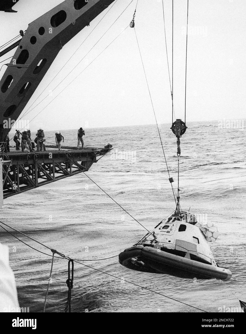 A crane swings the Apollo 8 spacecraft up from the surface of the ...
