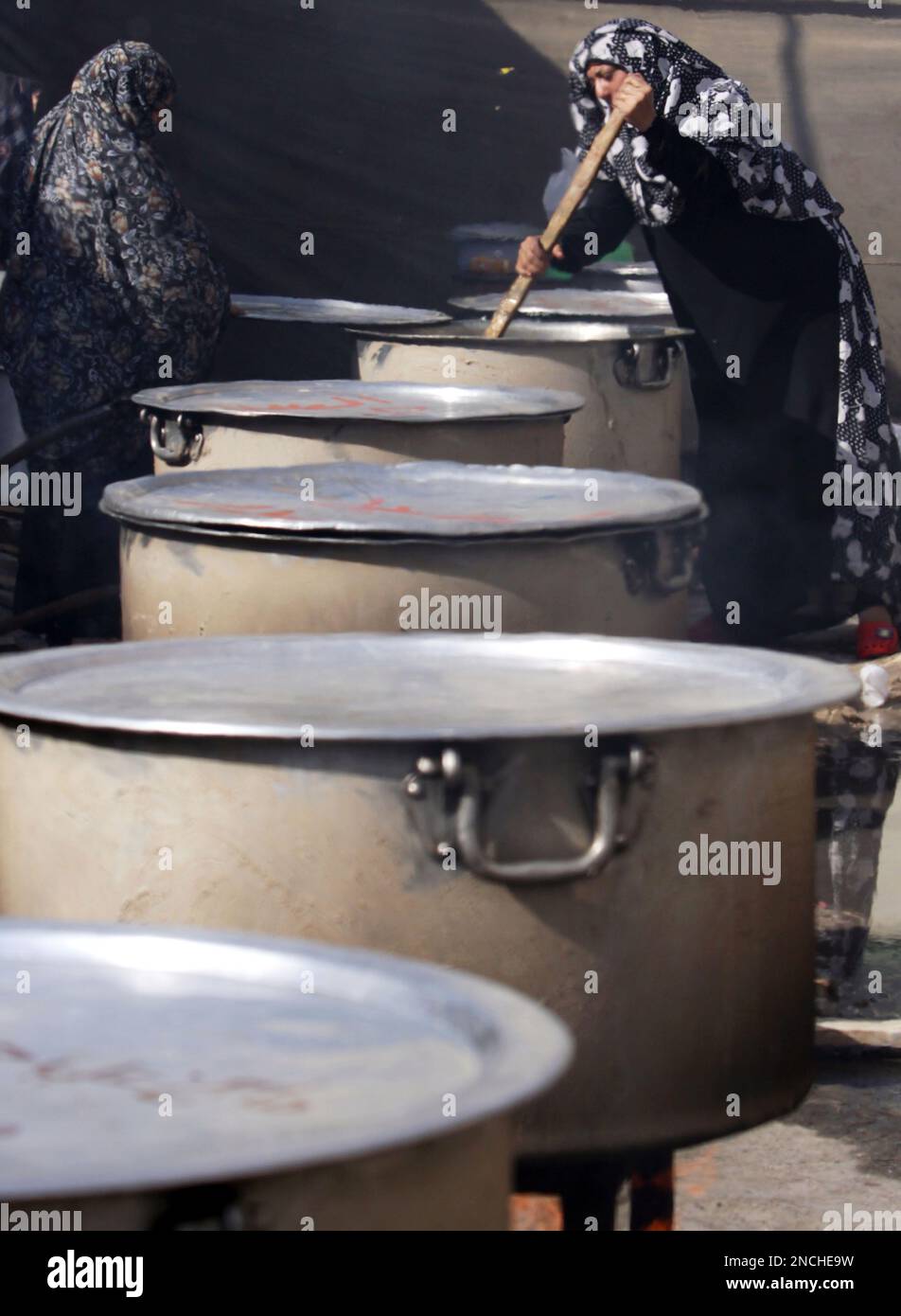 Bahraini women stir a steaming pot of stew Sunday, Dec. 12, 2010, in ...
