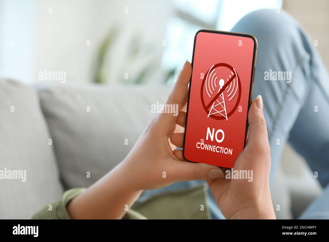 Woman holding mobile phone with text NO CONNECTION on screen at home ...