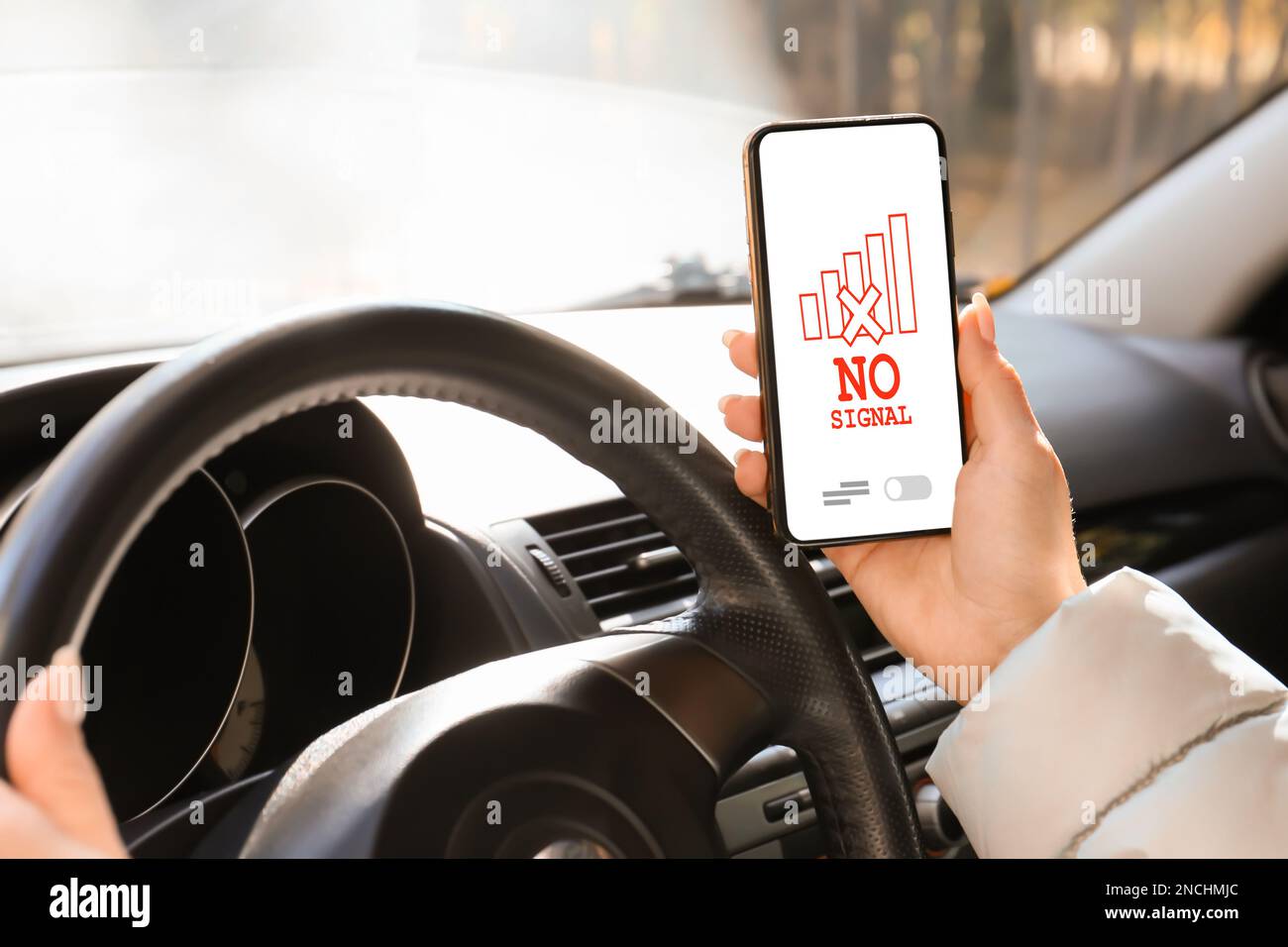 Woman holding mobile phone with text NO SIGNAL on screen while driving ...
