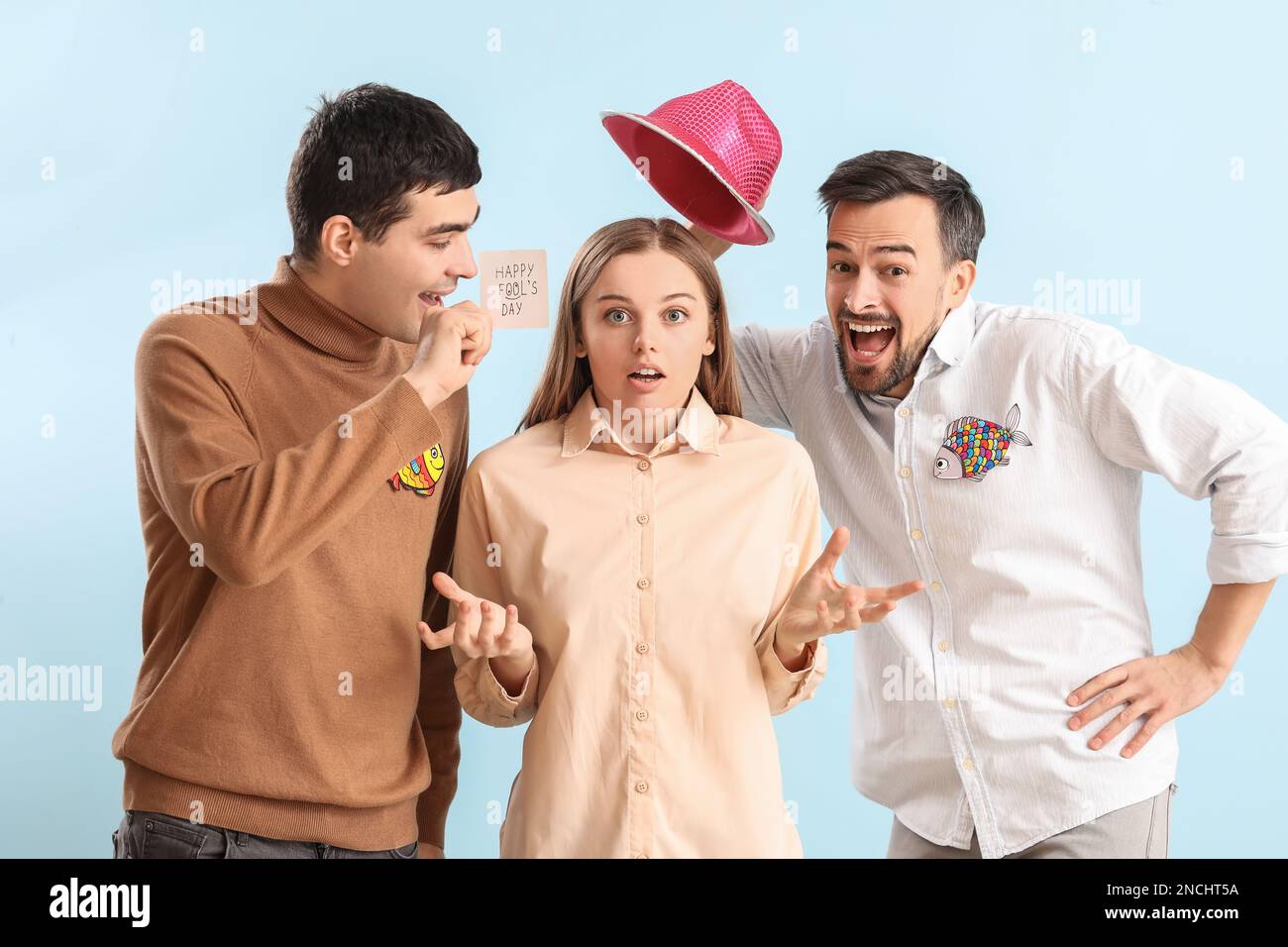 Young men playing a prank on their colleague against blue background ...