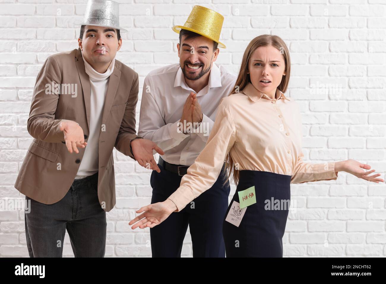Young men playing a prank on their colleague against white brick ...