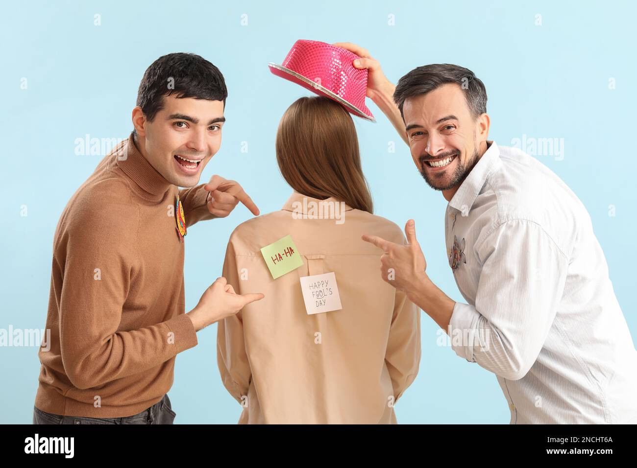 Young man playing a prank on their colleague against blue background ...