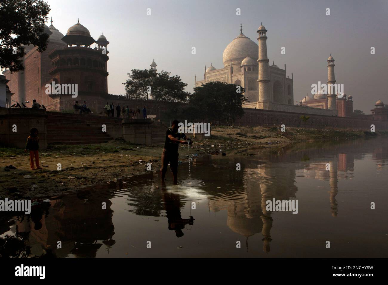 A hindu devotee offers milk to the river Ganges at the back side of the ...