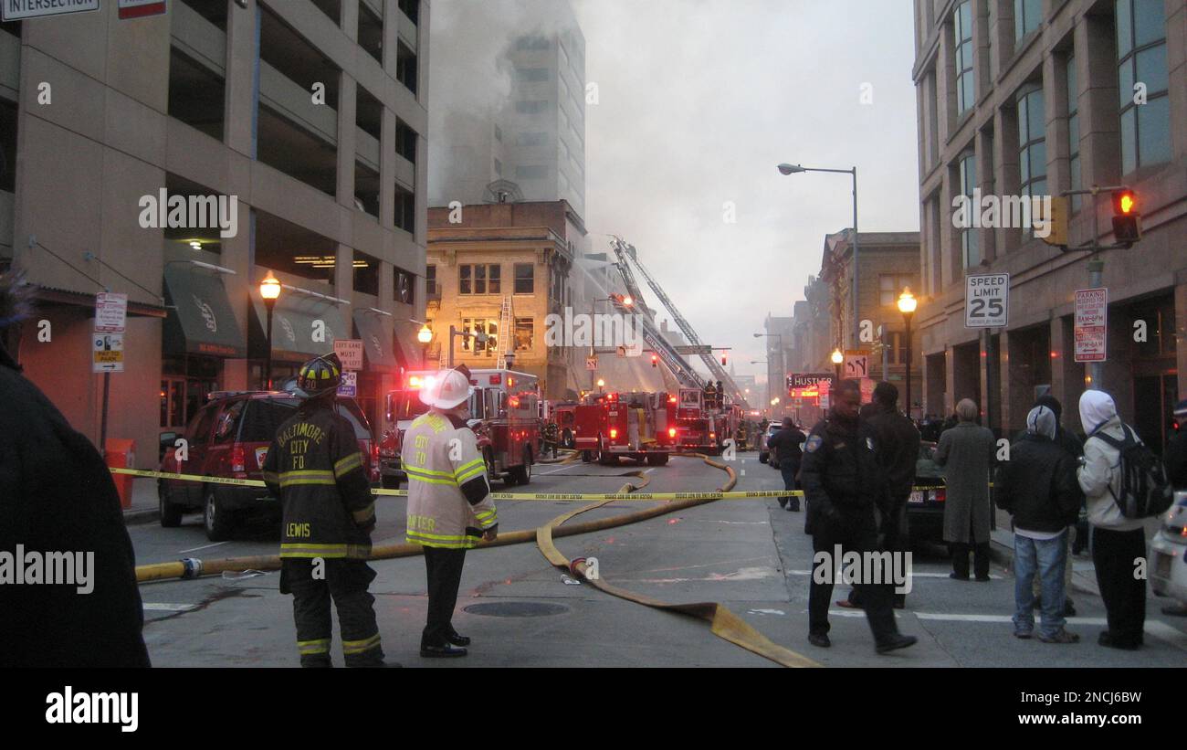 Firefighters work the scene of a multi-alarm blaze in a row of strip ...
