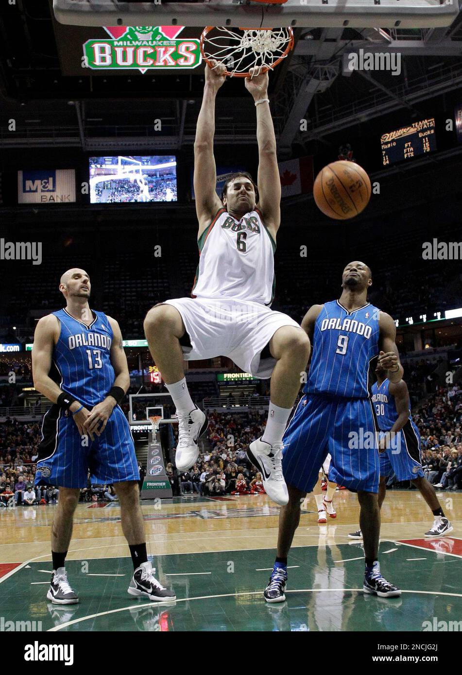 Milwaukee Bucks' Andrew Bogut (6) dunks in front of Orlando Magic's Marcin Gortat (13) and ...