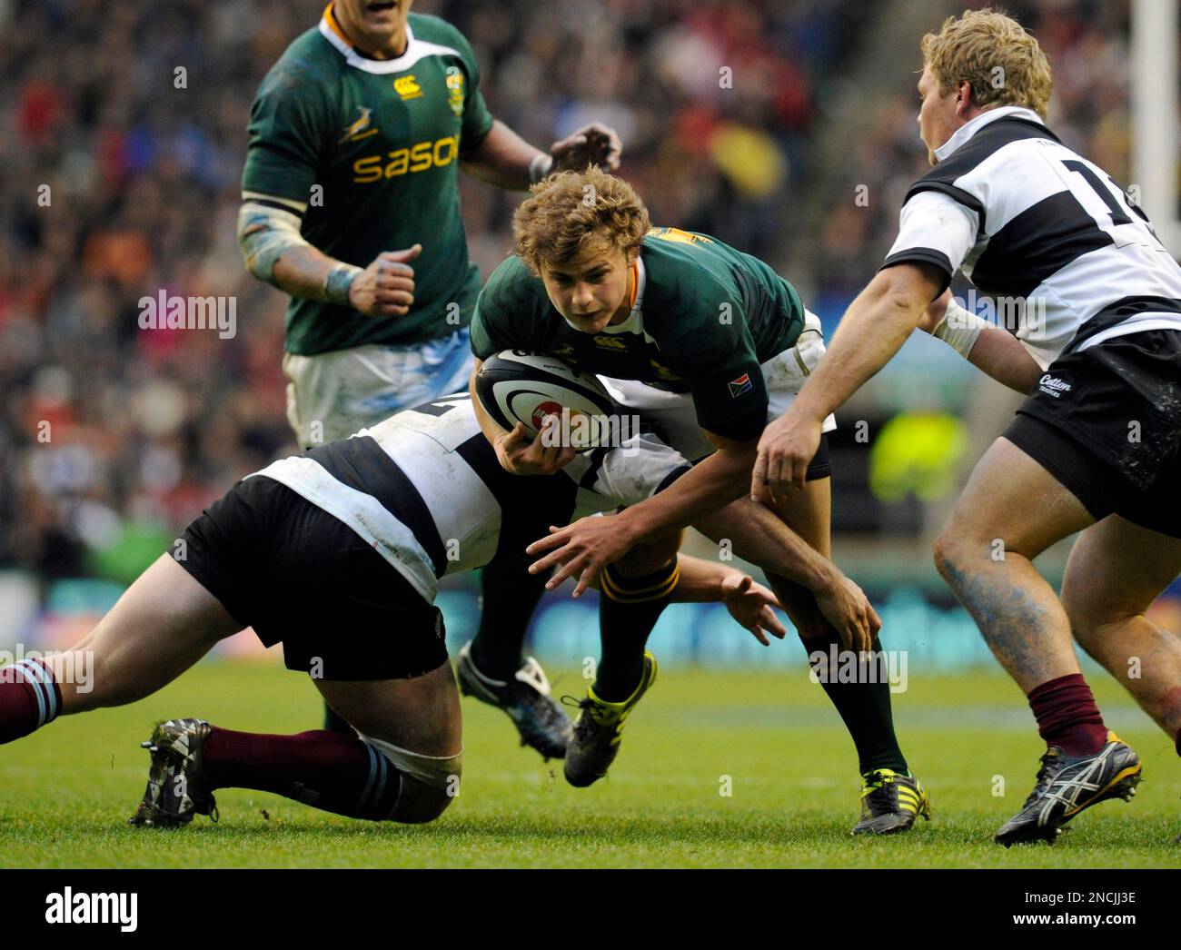 South Africa's Patrick Lambie, center, is tackled by Barbarians player ...