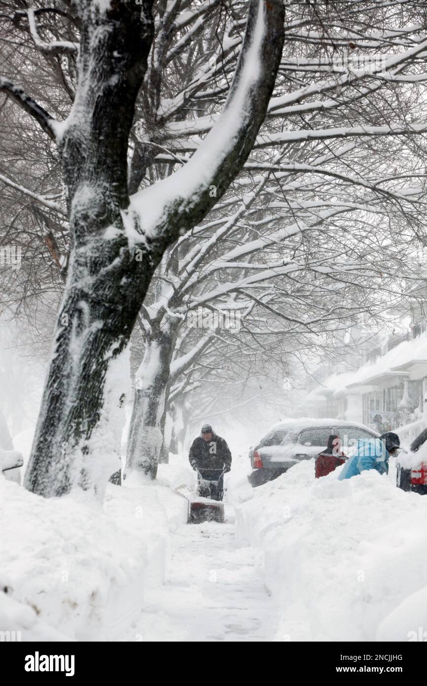 Ken Kobus clears snow from a sidewalk during a winter snow storm in ...
