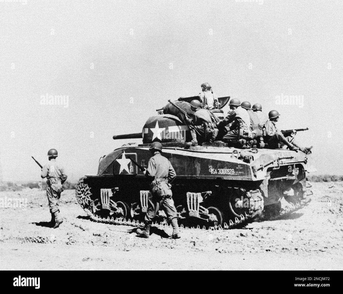 U.S. Army infantrymen ride and follow a General Sherman M-4 tank as a ...