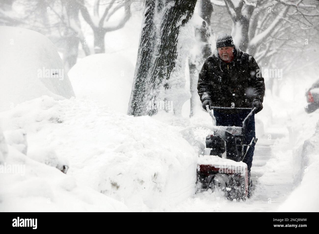 Ken Kobus clears snow from the sidewalk during a winter snow storm in ...