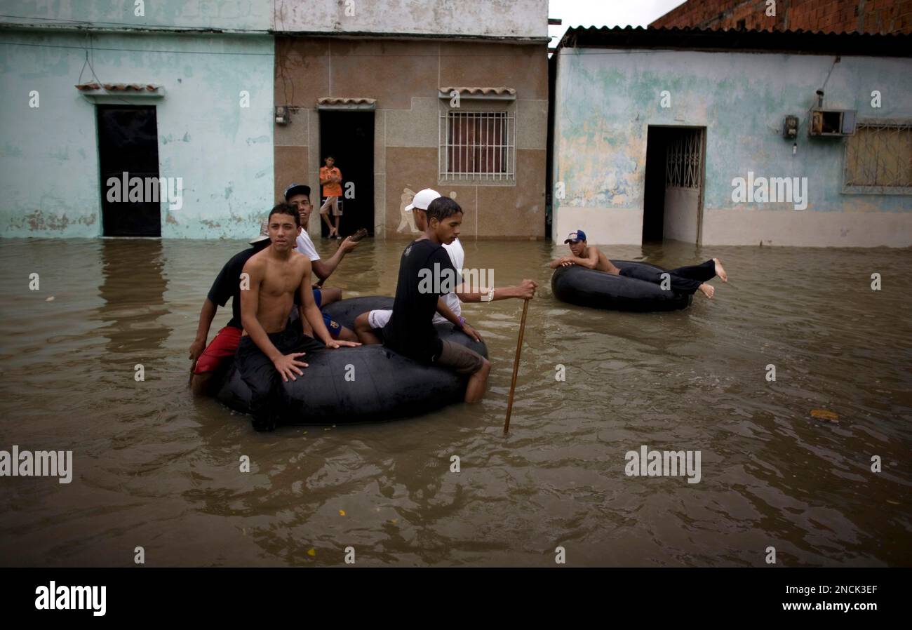 People float on inner tubes through a flooded street in Higuerote ...