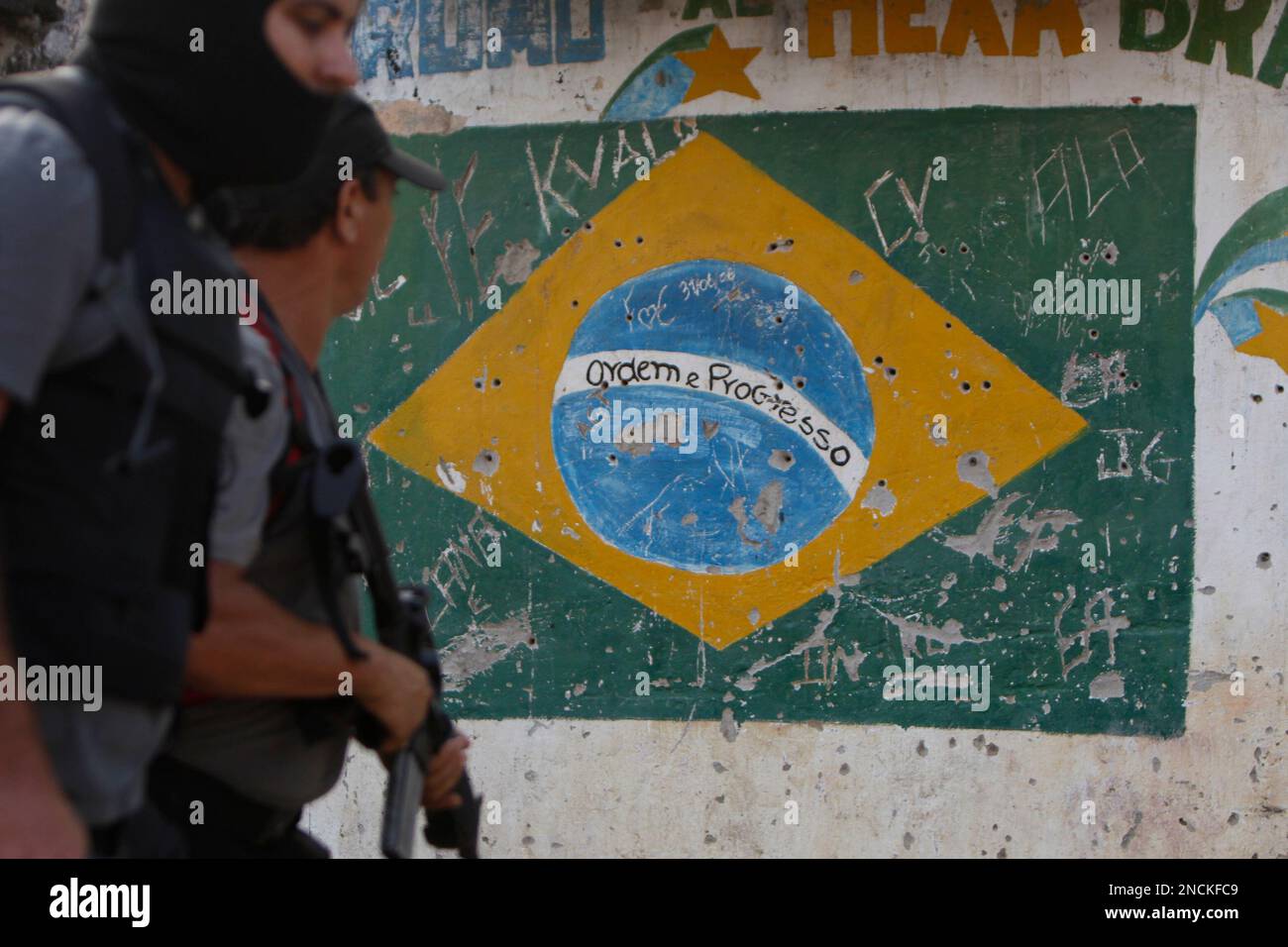 Policemen walk past a wall with a drawing of a Brazilian flag marked ...