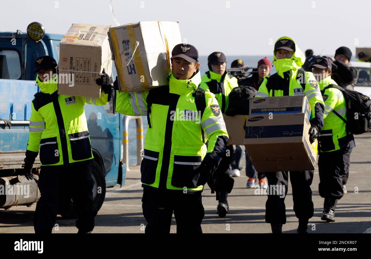 South Korean police officers carry boxes at a port on the Yeonpyeong ...