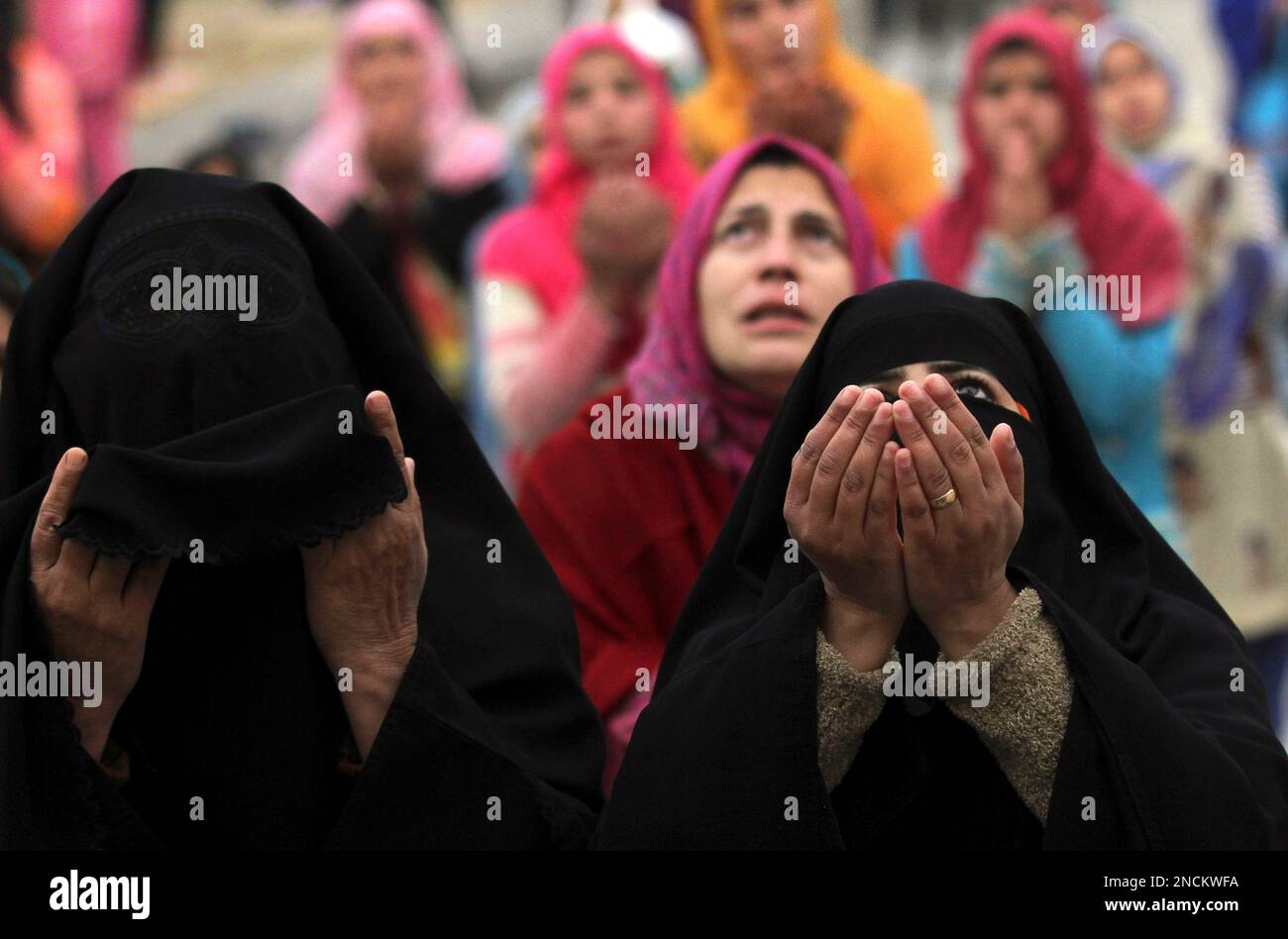 Kashmiri Muslim women raise their hands as the head priest, unseen ...