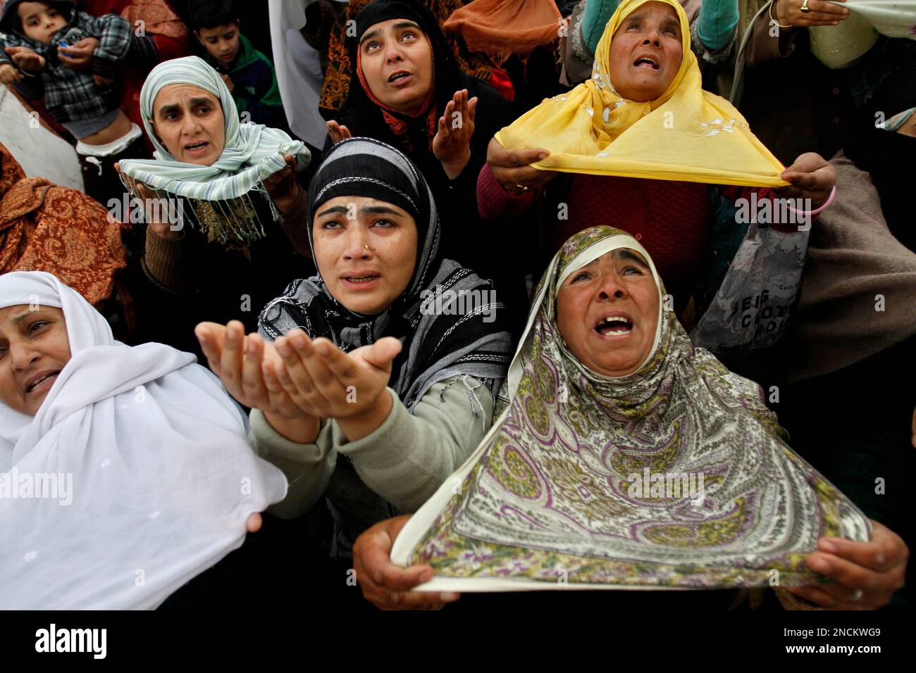 Kashmiri Muslim women raise their hands as the head priest, unseen ...