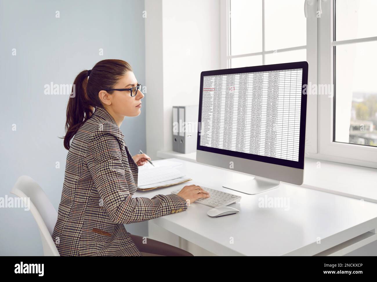 Young attractive Caucasian business woman looks at large monitor with ...