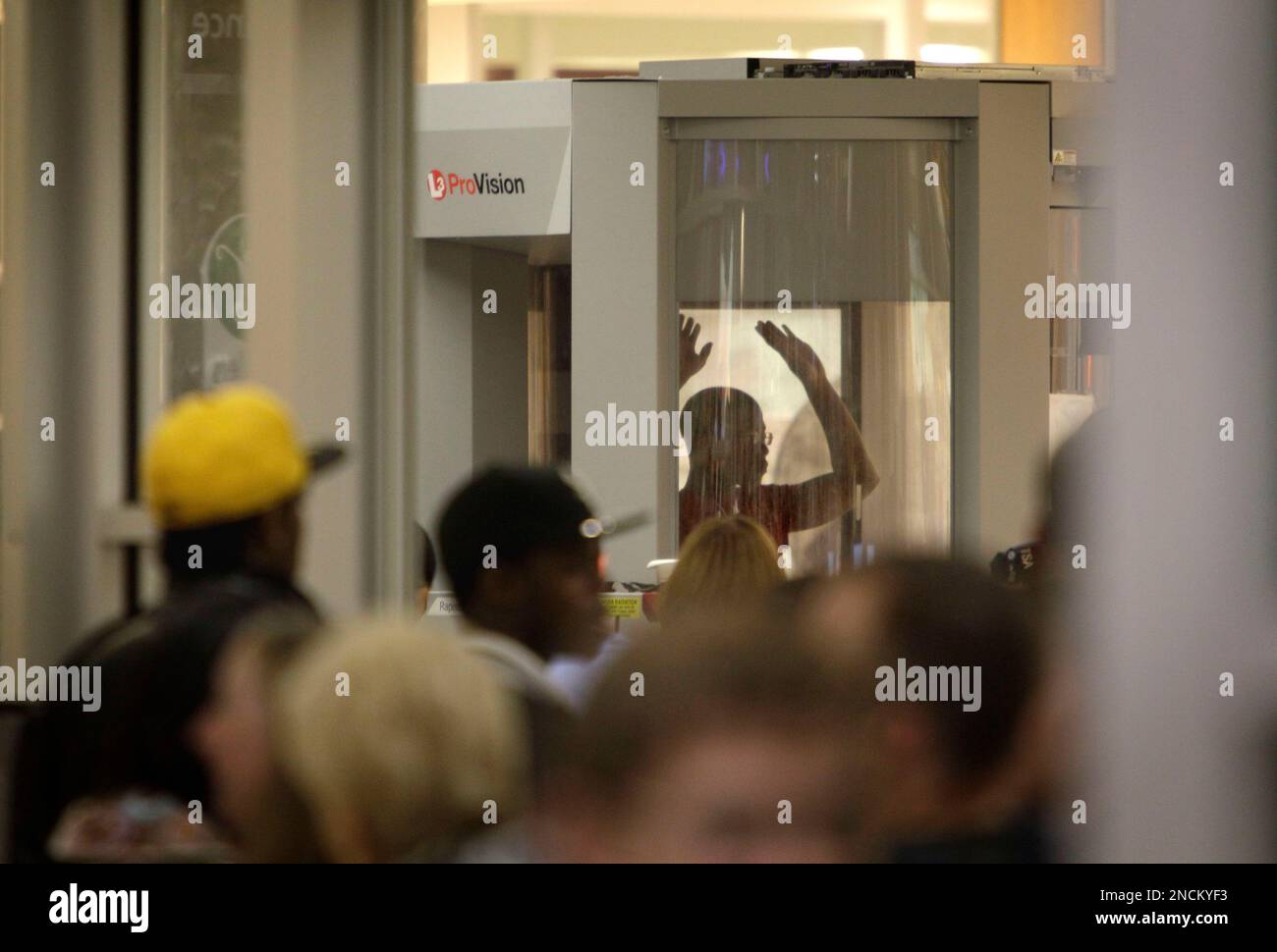 A passenger stands in a full body scan machine at a security checkpoint ...