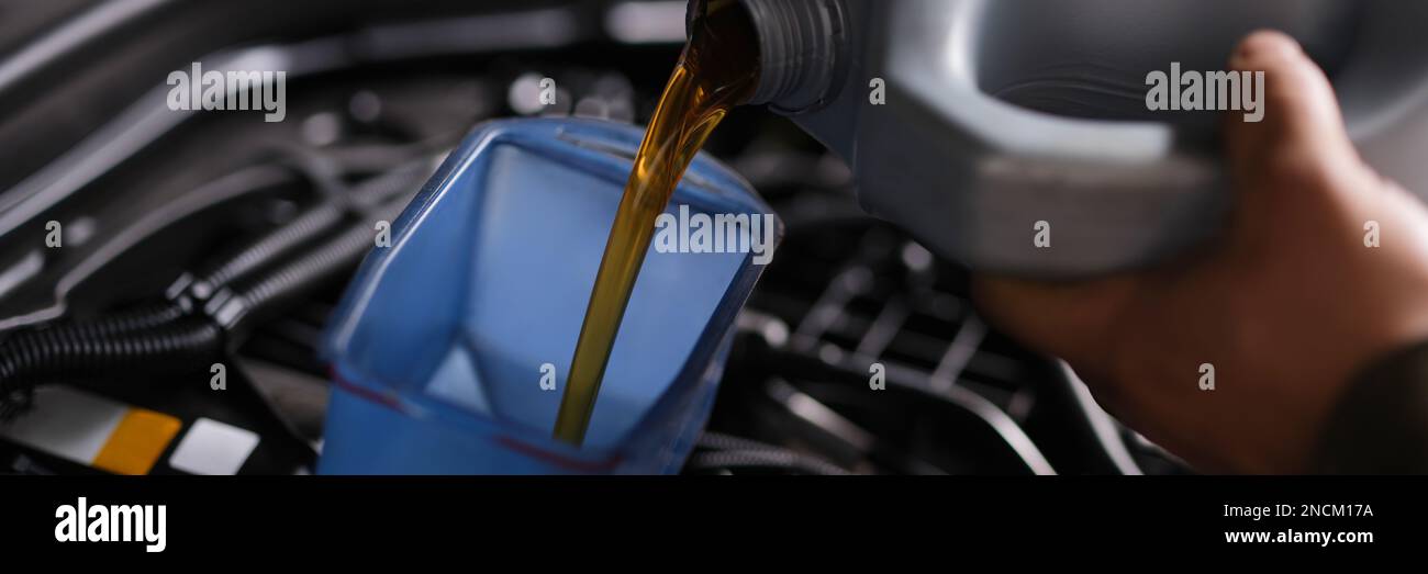 Auto mechanic replaces and pours fresh oil into engine at service ...