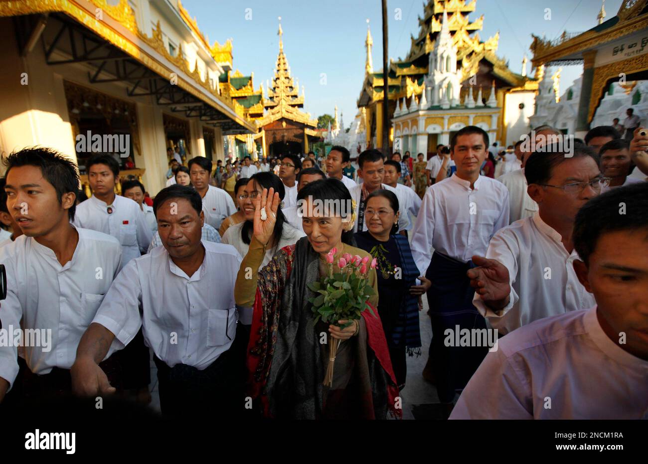 Myanmar's pro-democracy leader Aung San Suu Kyi, center, waves to devotees as she arrives at ...