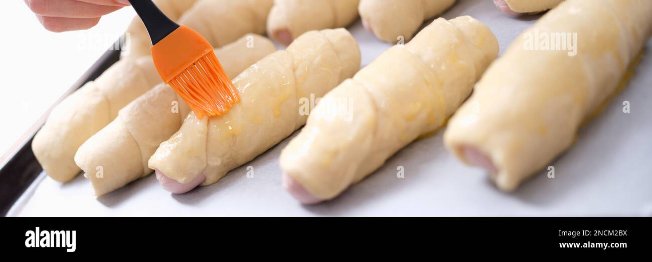 Female cook greases sheet of dough with melted butter and prepares ...