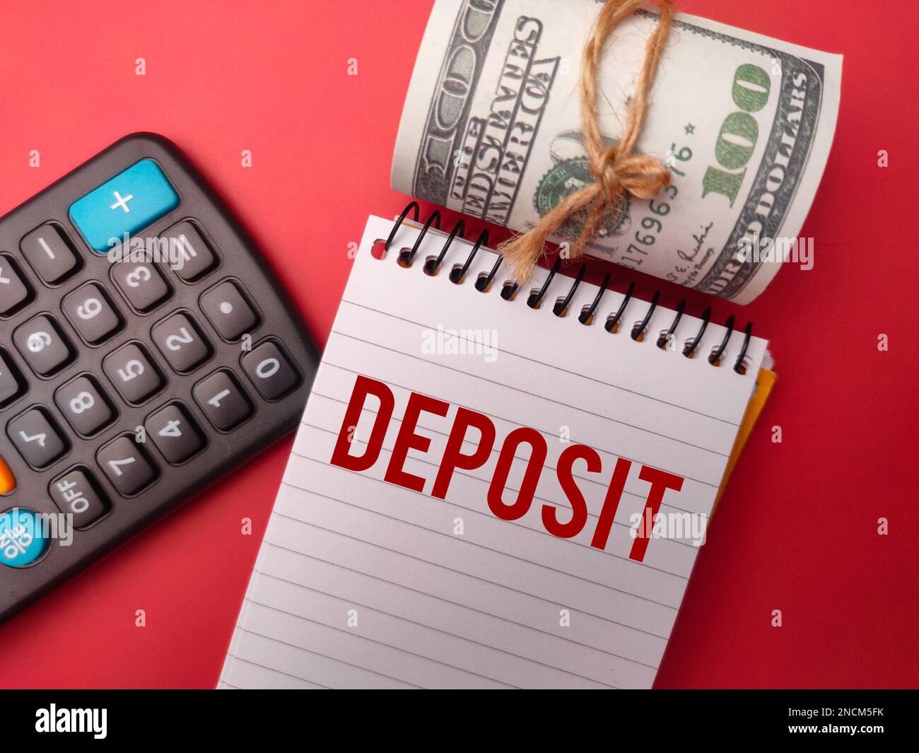 A top view of a calculator with banknotes and notebook with the word ...