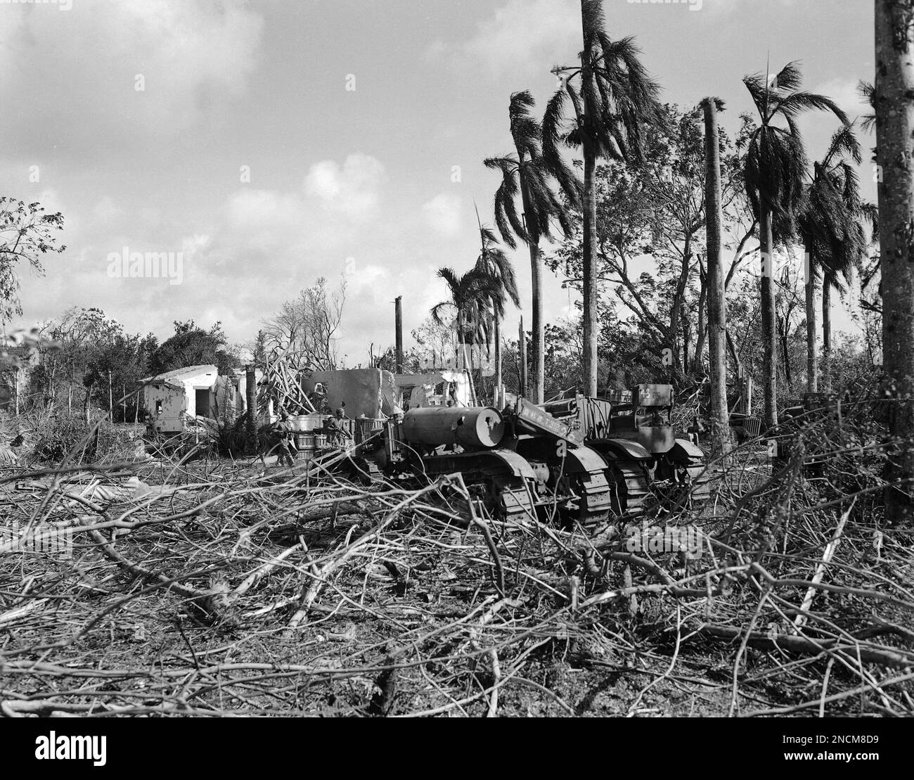Captured Japanese construction equipment and rubble of quartermaster headquarters in background ...