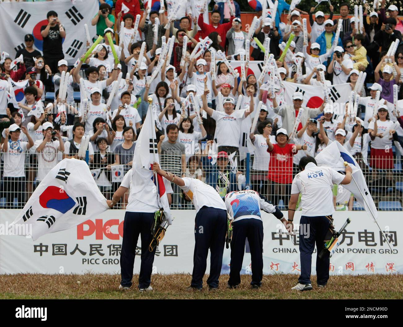 South Korea's archery team and coach bow in front of South Korean fans ...
