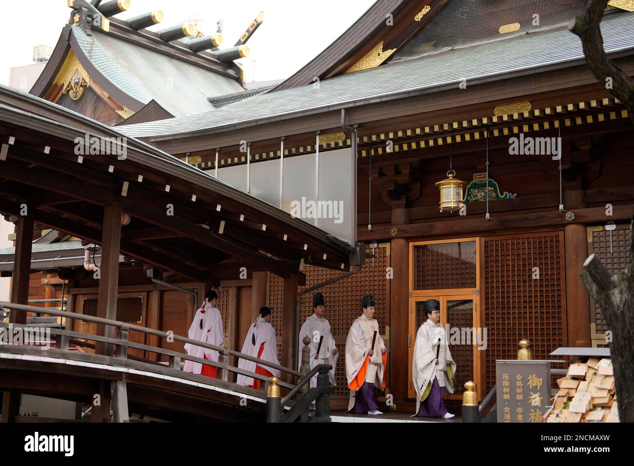 Shrine priests and maidens walk into the main shrine at the Yushima ...