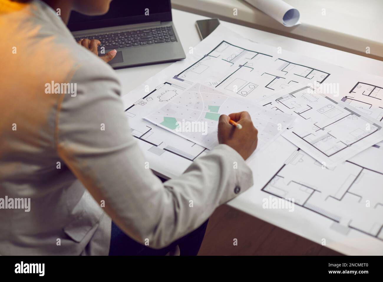 Woman architect working on blueprints and using urban plans and ...