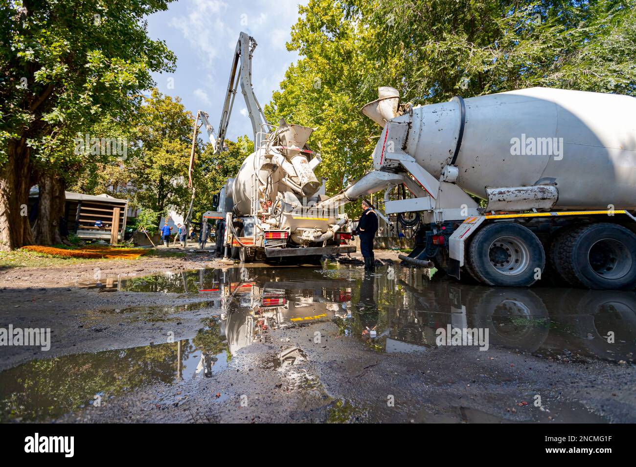 Pouring fresh concrete from mixer truck over ramp to another that has a ...