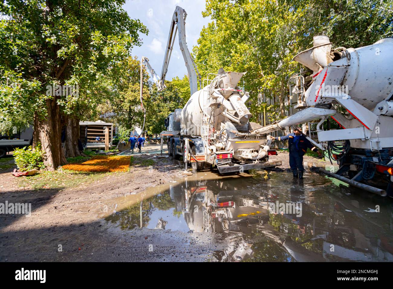 Pouring fresh concrete from mixer truck over ramp to another that has a ...