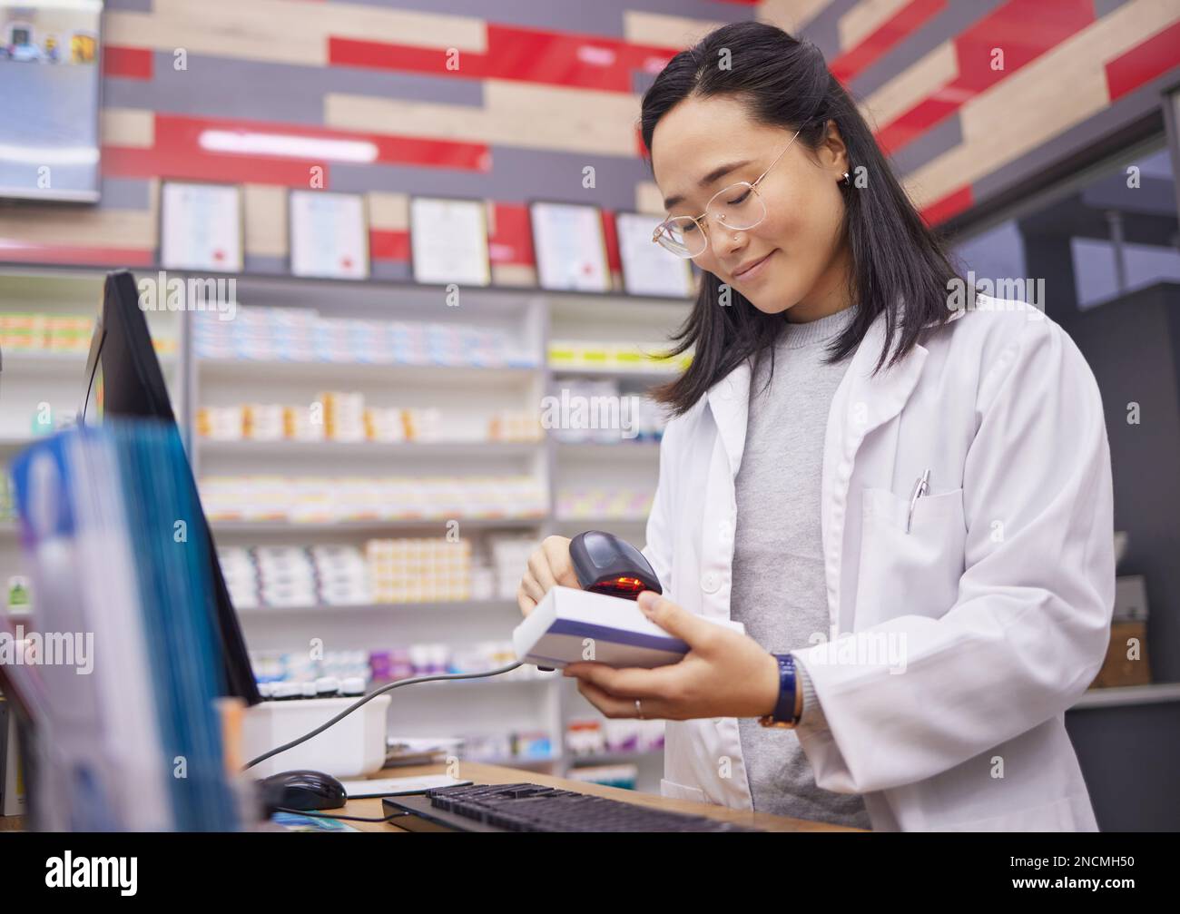 Pharmacy, smile and asian woman scanning medicine at checkout counter ...