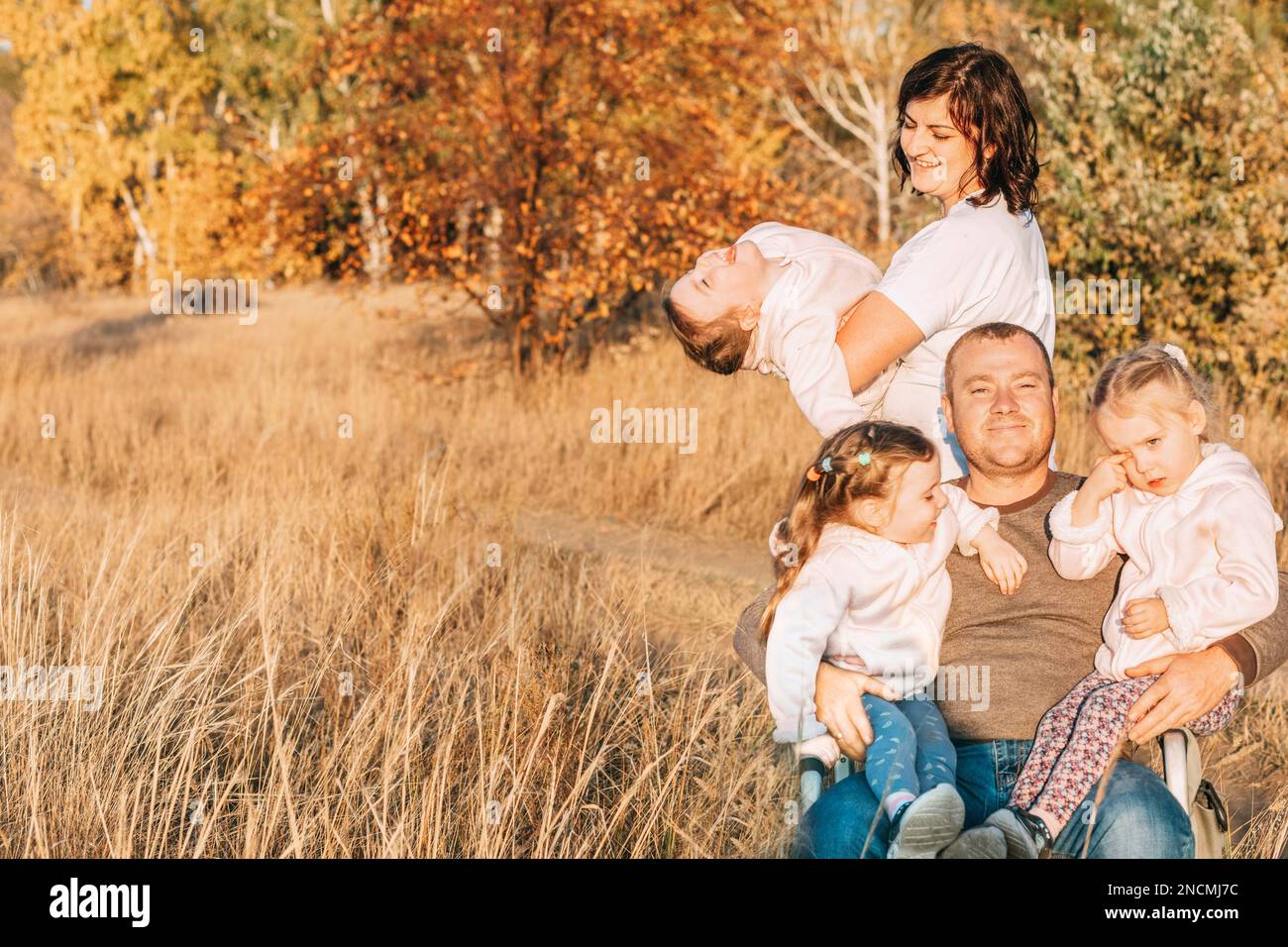 Family with triplet on a walk. Happy father and mother hold children in ...