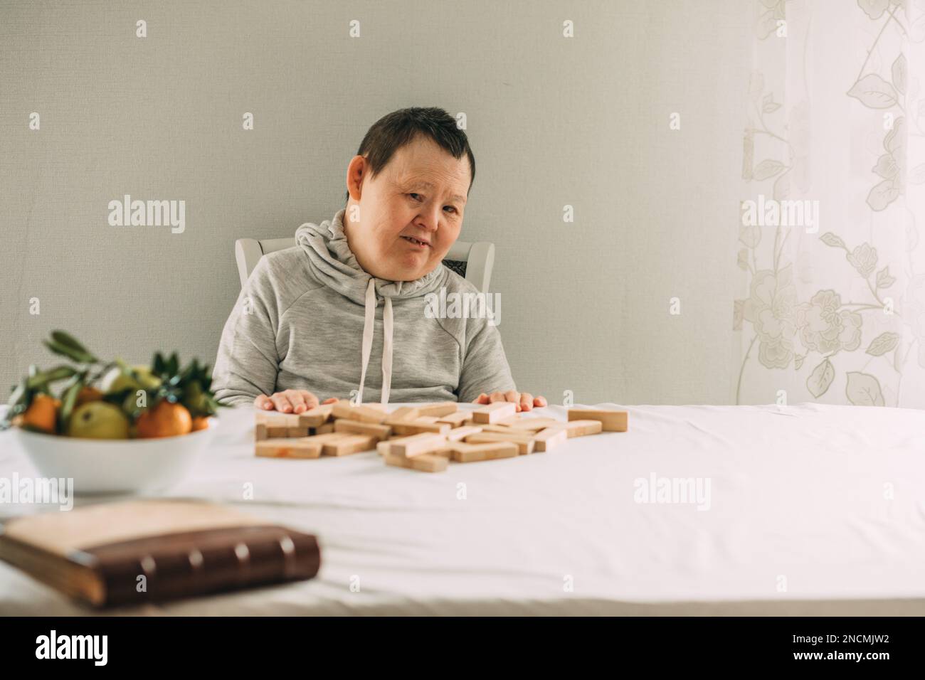 An elderly woman with down syndrome builds towers of their wooden toy ...