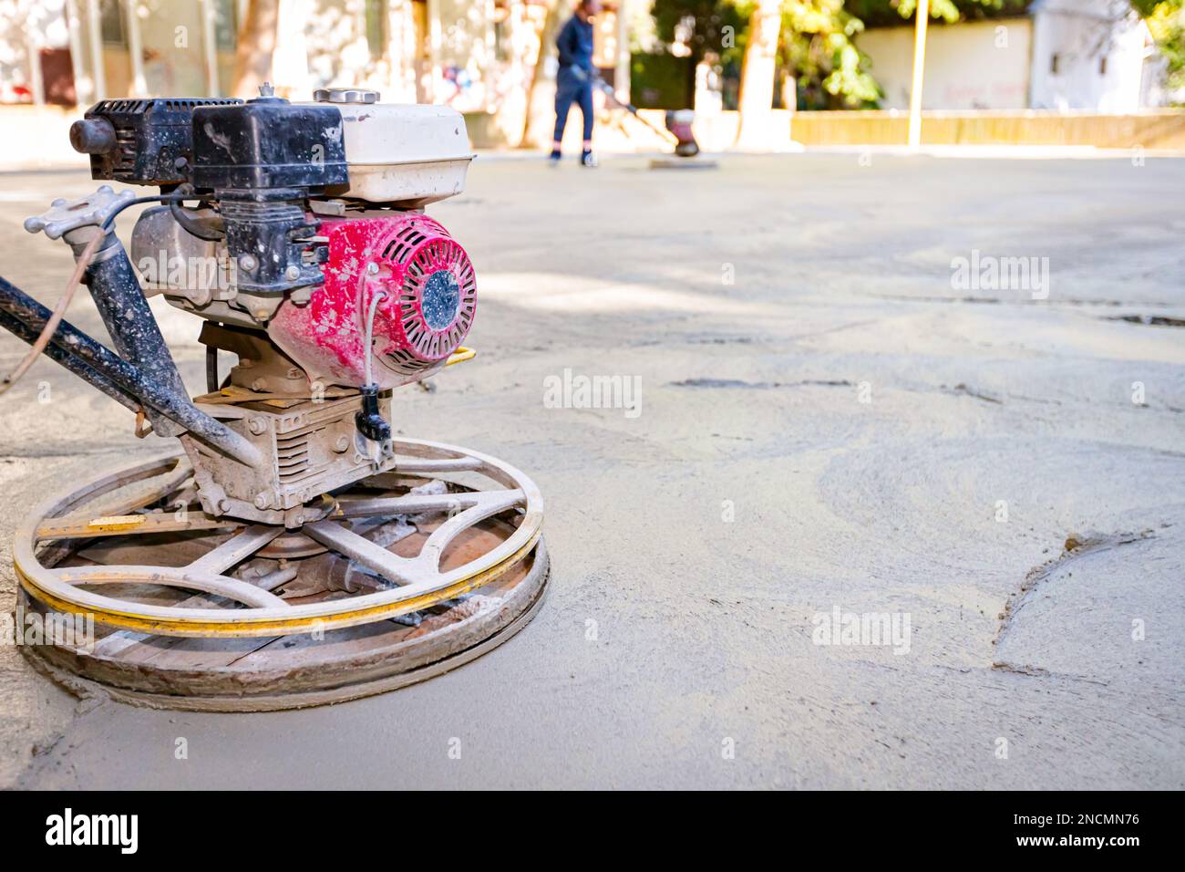 Worker using self-leveling power trowel machine with gas engine has ...