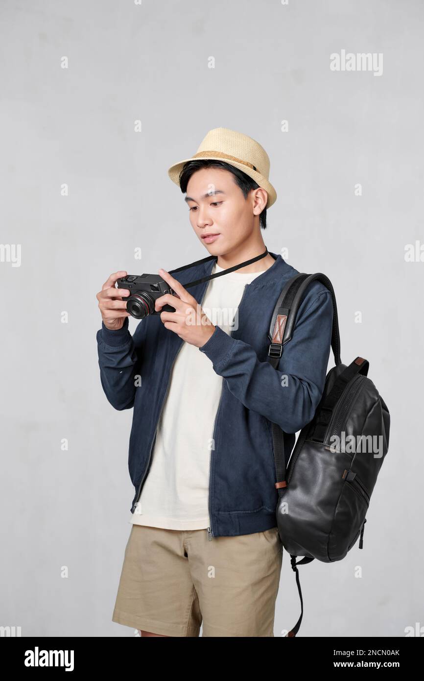 Young man carrying rucksack and using camera on white background Stock ...