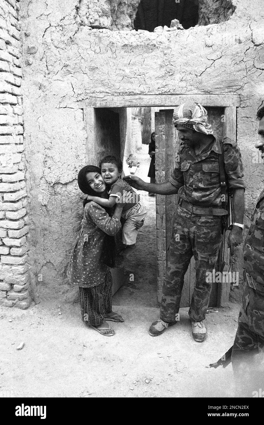 An Iraqi soldier comforts a crying baby held up by his smiling sister ...