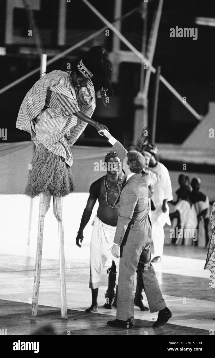 President Jimmy Carter reaches high up to shake with a stilt-wearing ...