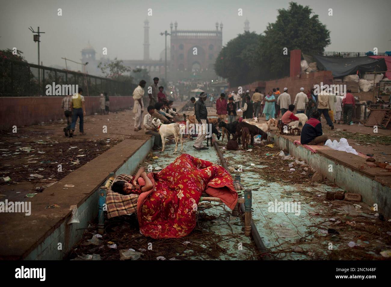 An Indian youth sleeps on a cot outside the Jama Masjid mosque, one of ...