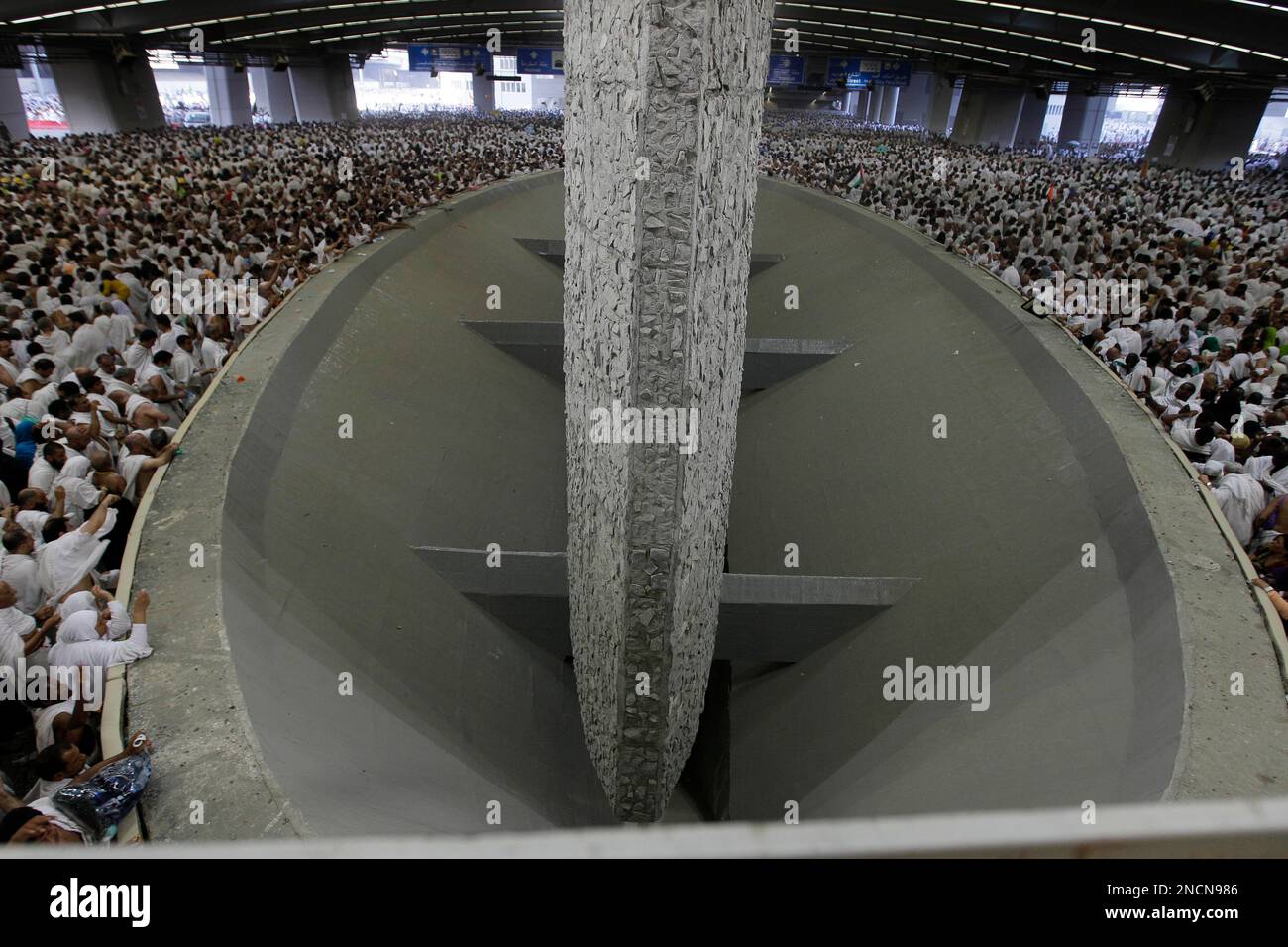 Muslim pilgrims cast stones at a pillar, symbolizing the stoning of ...