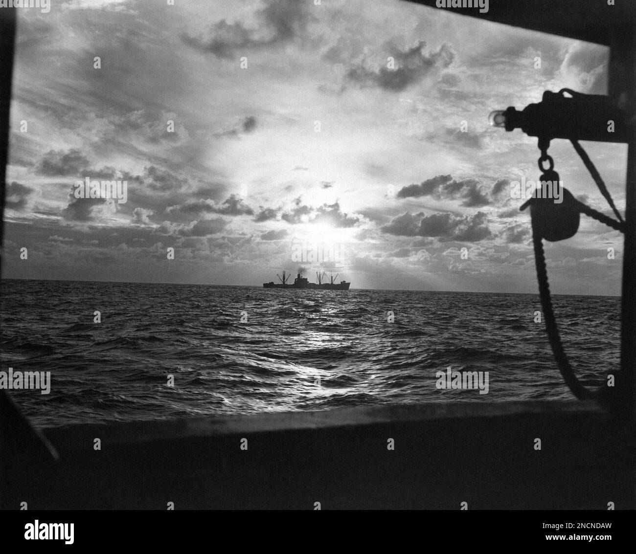 Silhouetted against an angry sunset sky, one of the ships of convoy en ...