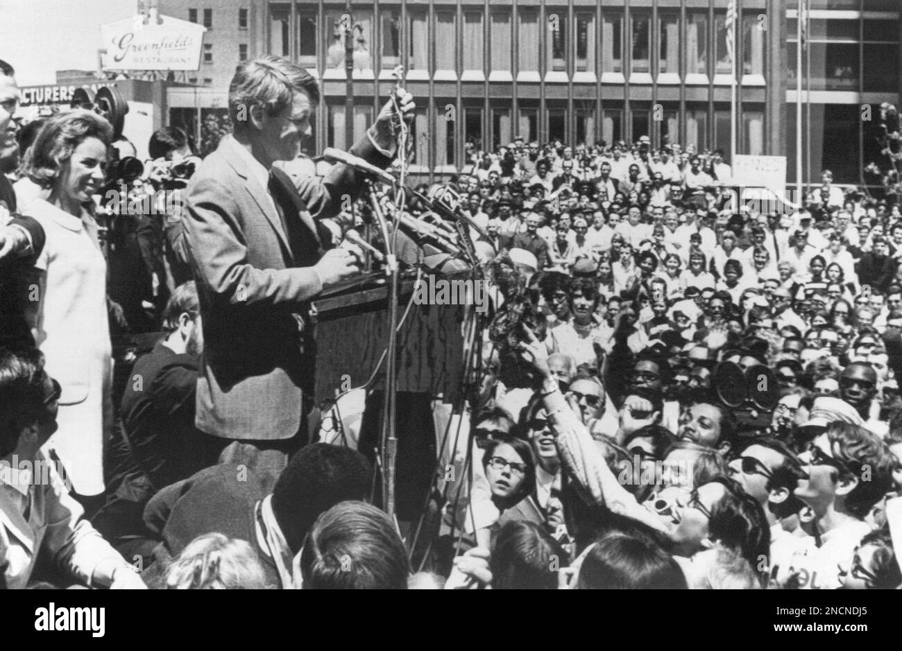 Sen. Robert F. Kennedy holds a flower tossed to him by the woman whose ...