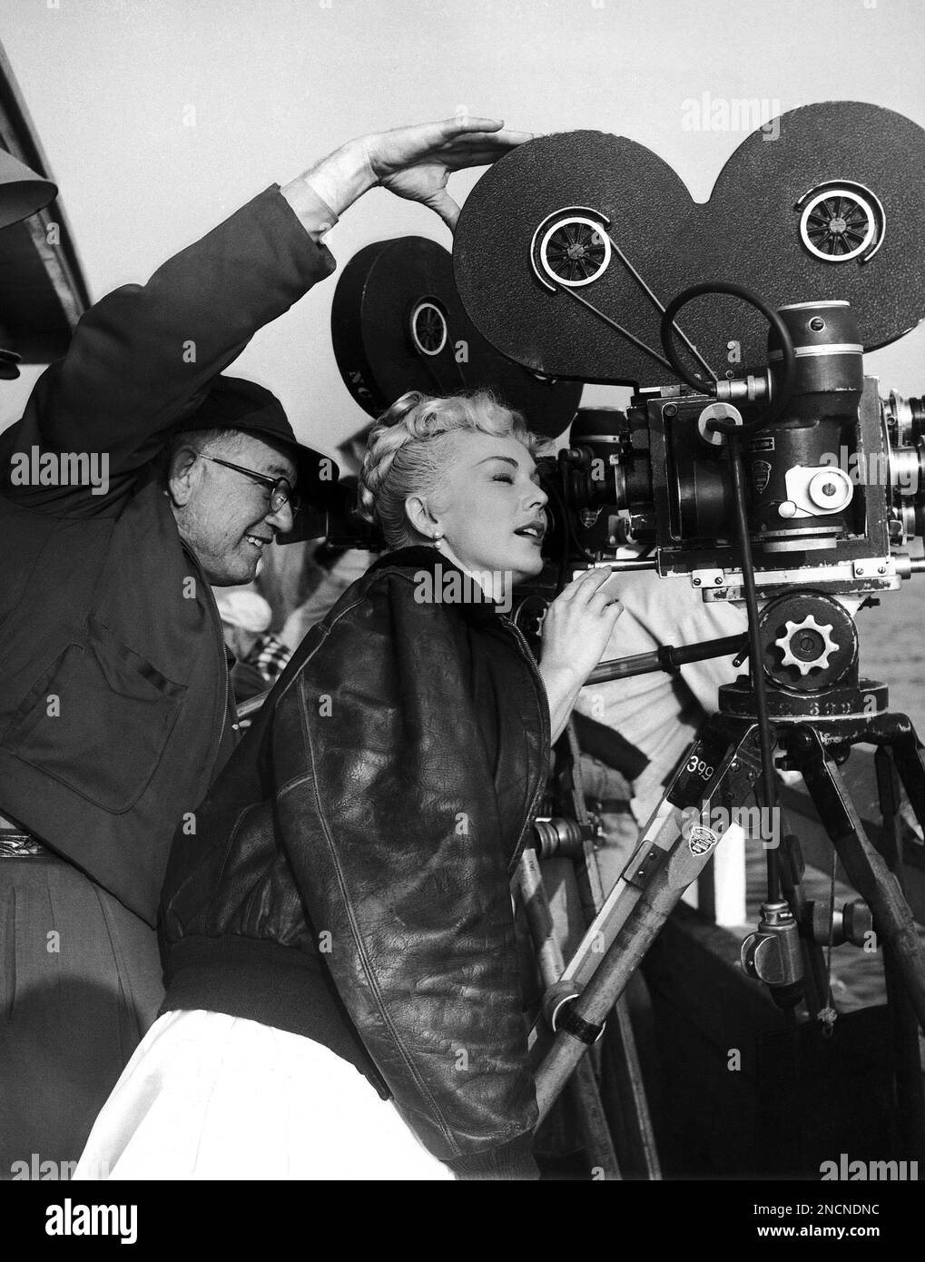 Eva Gabor watches through the camera finder as cameraman Charles Van ...