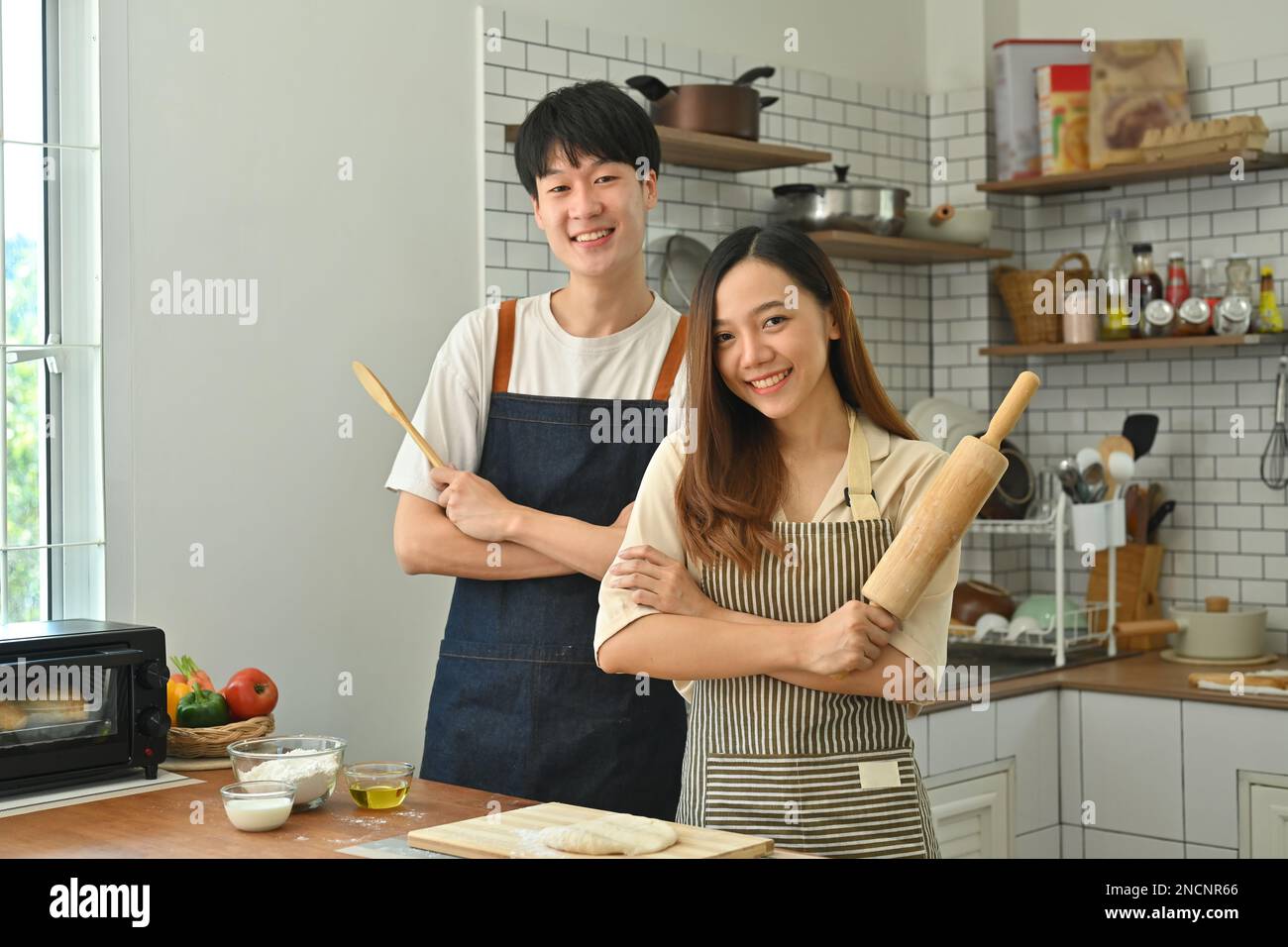 Happy married couple with rolling pins in their hand, preparing dinner ...