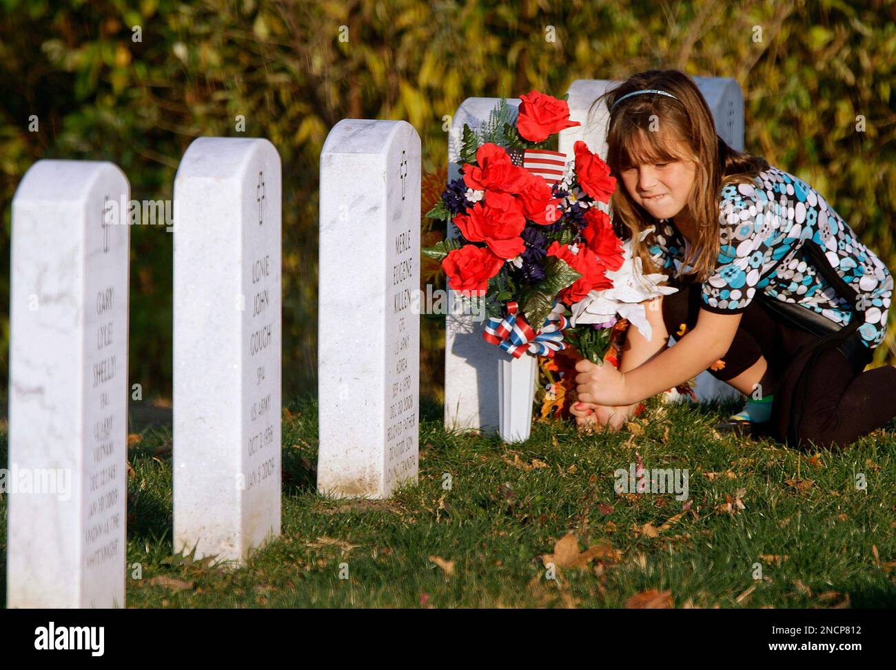 Madelyn Cox, 5, pushes flowers into the soil of a relative's grave in ...